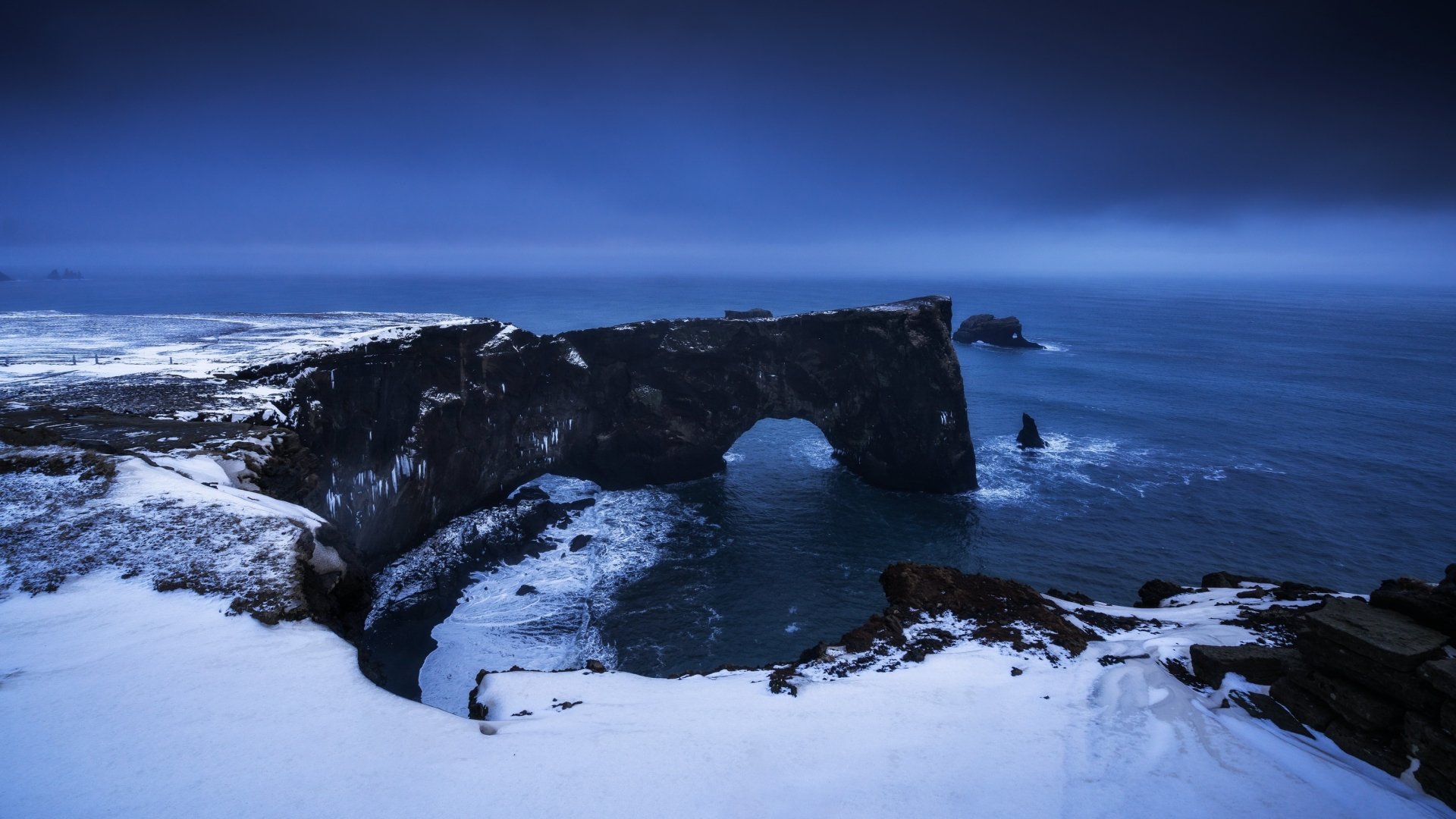 Frozen Ocean Archway: Snow-Covered Cliffs Meet the Horizon in HD
