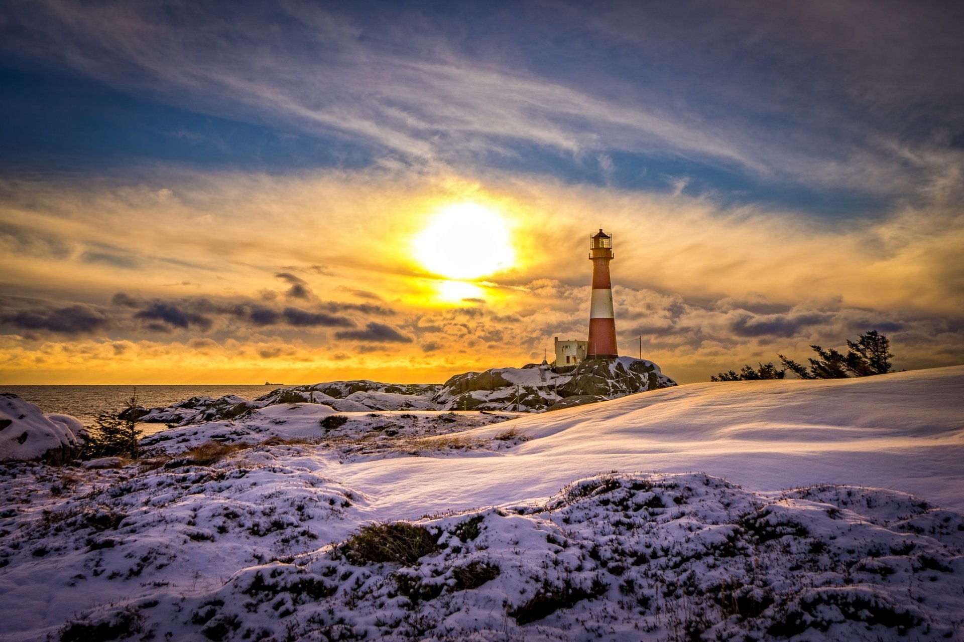 Winter Lighthouse at Sunset: Horizon Glow over Snowy Clouds – HD Wallpaper